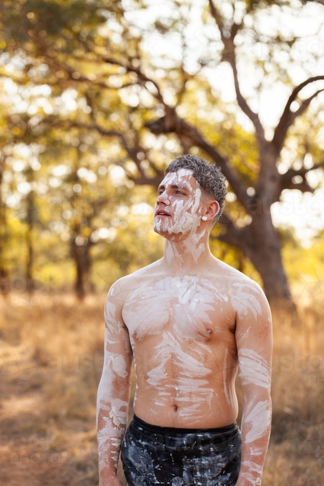 Image of Aboriginal teen looking up and away with bokeh bushland ...
