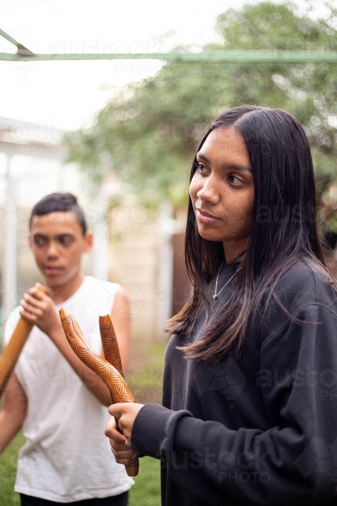 Image of Aboriginal teenage girl with musical sticks in her backyard ...