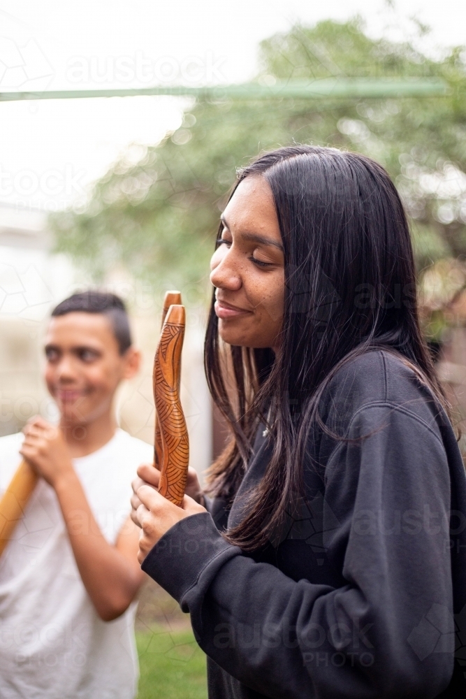 Image of Aboriginal teenage girl with musical sticks in her backyard ...