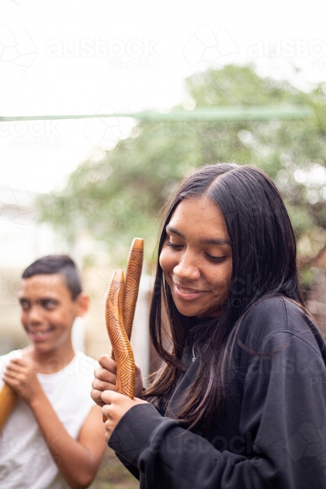 Image of Aboriginal teenage girl with musical sticks in her backyard ...