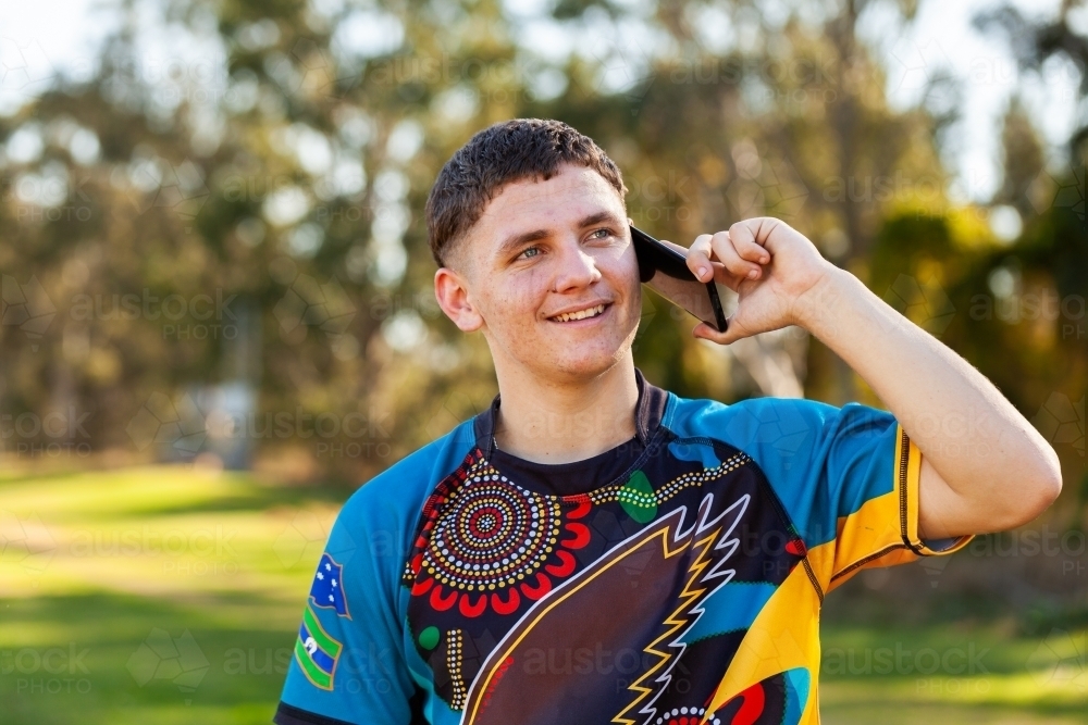 Image of Aboriginal teenager using mobile phone to talk with mates ...