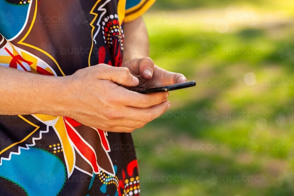 Image of Aboriginal teenager using mobile phone to text message ...