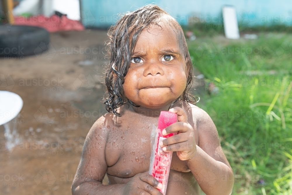 Image of Aboriginal toddler eating icy pole - Austockphoto