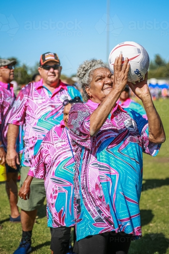 Image of Aboriginal woman at front of line throwing a netball ...