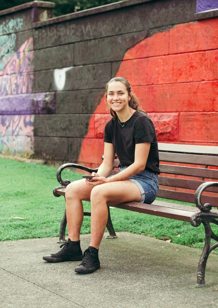 Image of Aboriginal woman sitting on a park bench with a painted flag ...