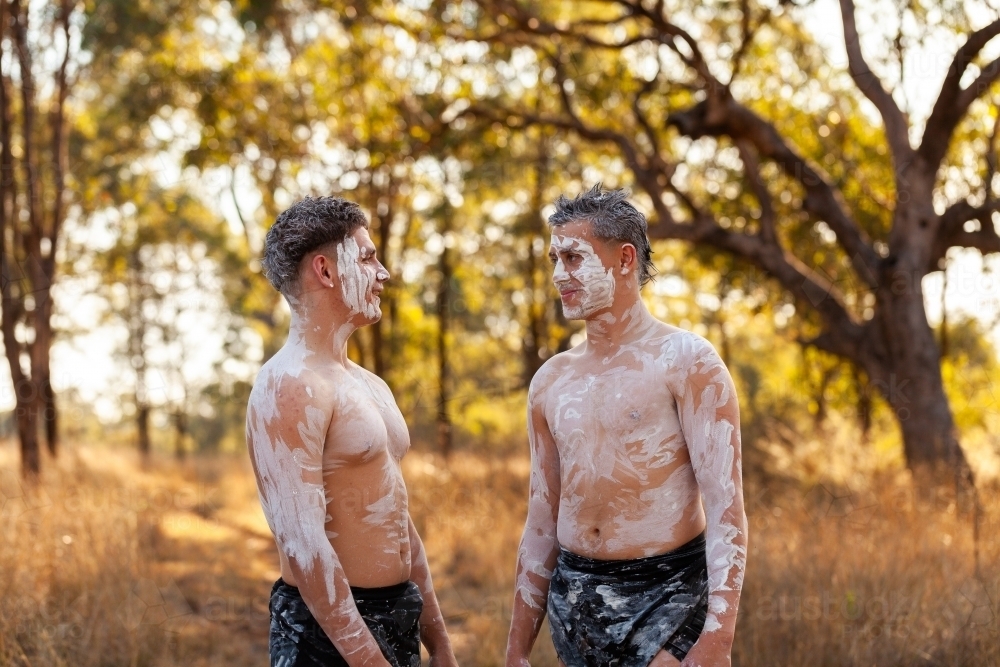 Image of Aboriginal young men in body paint talking together in bush ...