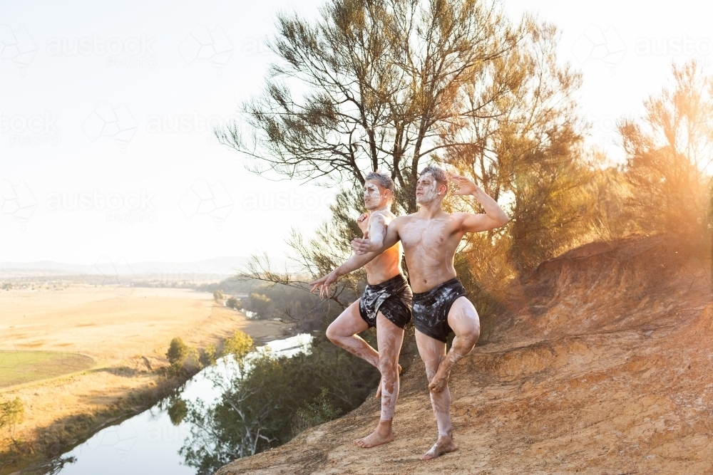 Image of Aboriginal young men pose in dance move on edge of cliff in ...