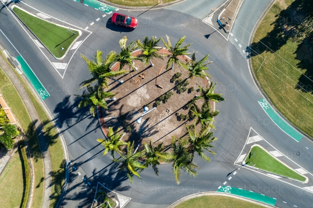 Image of Aerial drone view of red car entering a roundabout with palm ...
