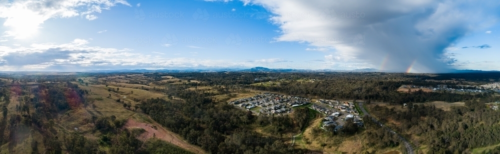 Image of Aerial panorama of double rainbows and rain cloud over edge of ...