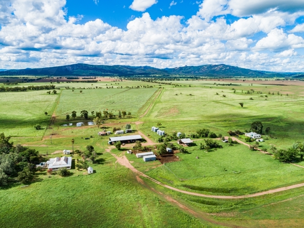Image of Aerial scene of farm sheds and house among green paddocks ...