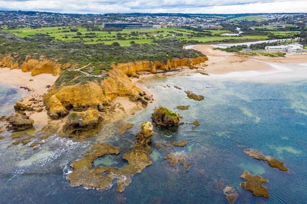 Image of Aerial view a rocky cliff jutting out into a calm ocean ...