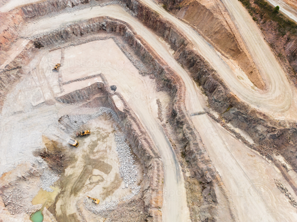 Image of Aerial view looking down into a quarry pit with machinery on ...