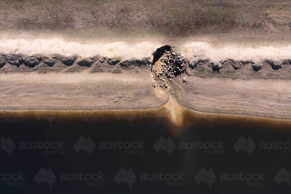 Image of aerial view looking down on dark water and dam bank where ...