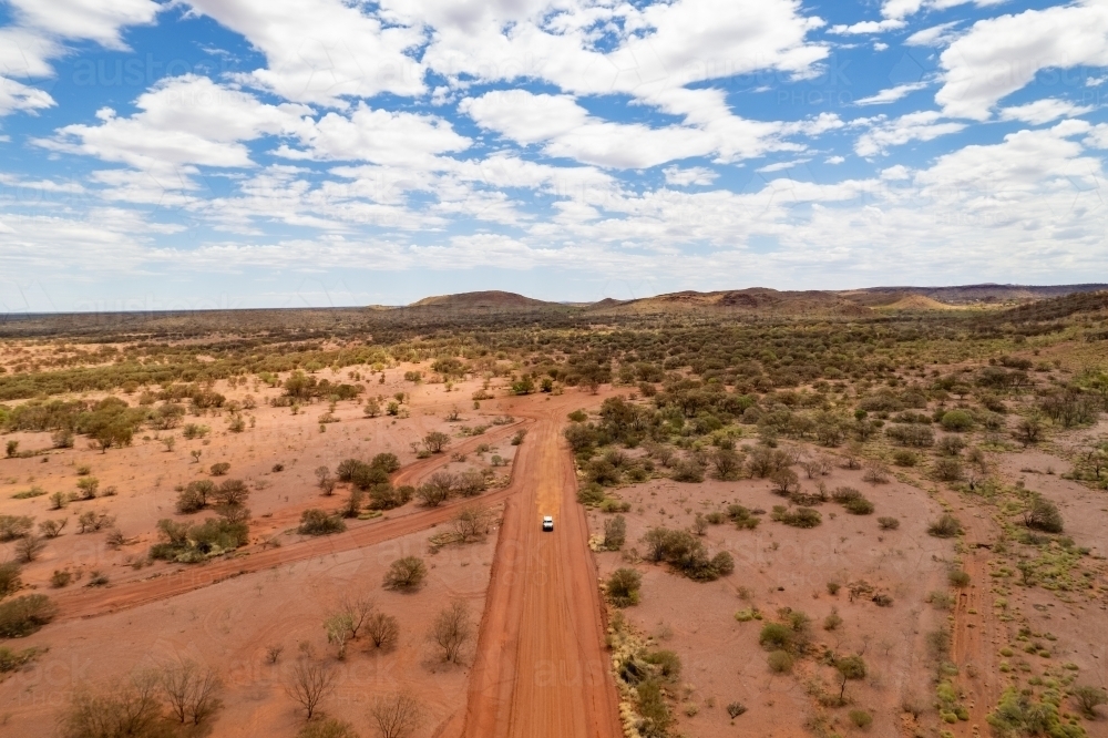 Image of Aerial view of a 4WD driving down an isolated dirt track in ...