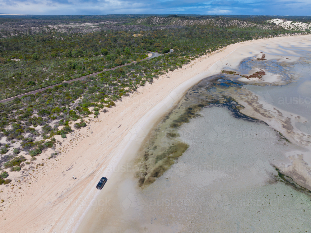 Image of Aerial view of a 4wd in a narrow beach between the sea and ...