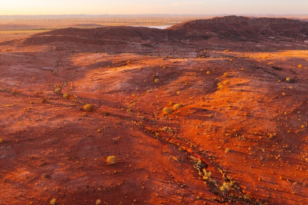 Image of Aerial view of a barren orange outback below a mountain range ...