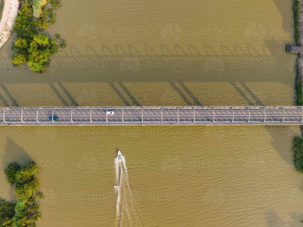 Image of Aerial view of a boat going under a steel bridge crossing a ...