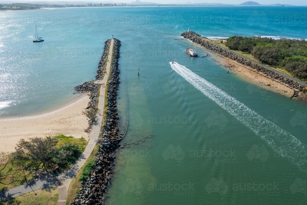 Image of Aerial view of a boat moving between rocky breakwaters and out ...