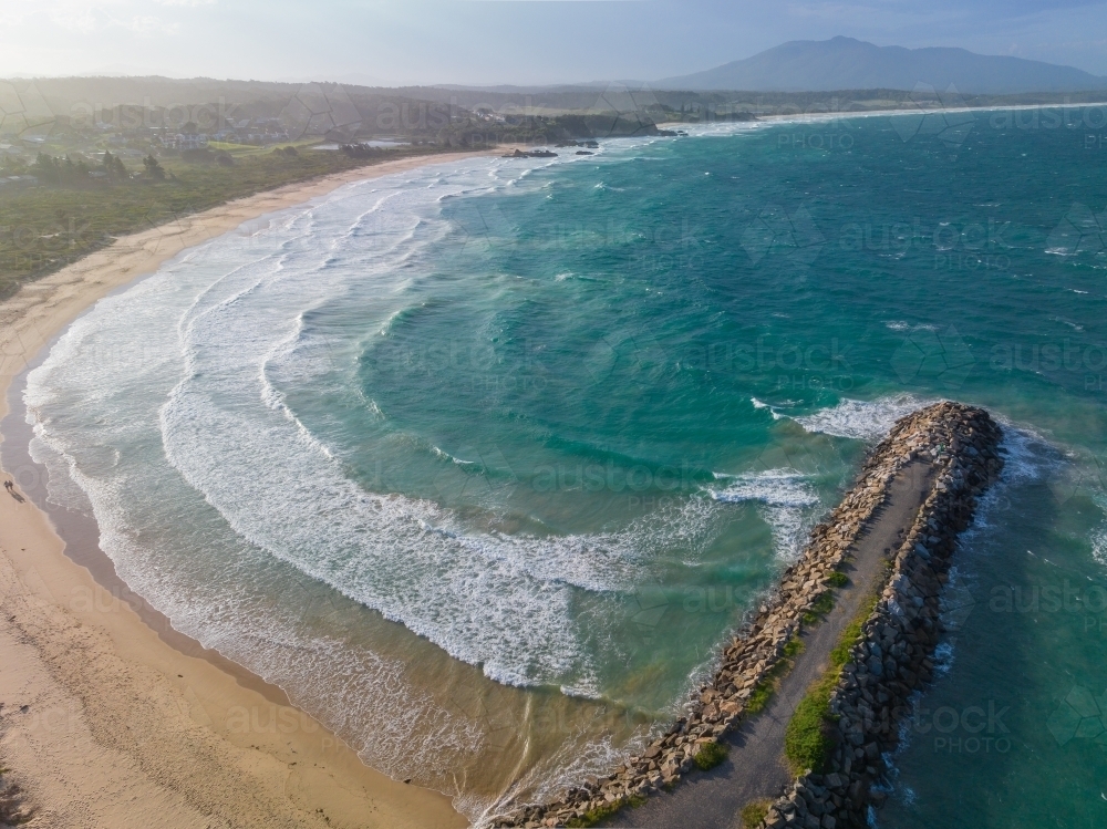 Image of Aerial view of a breakwater jutting out into waves on an ocean ...