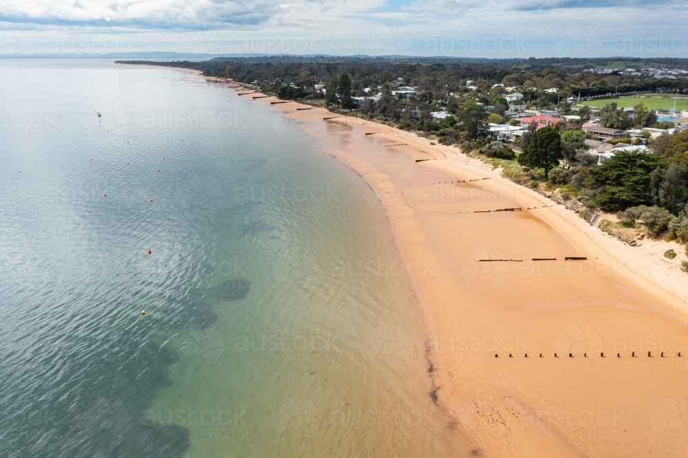 Image of Aerial view of a calm bay and golden sandy beach with lines of ...