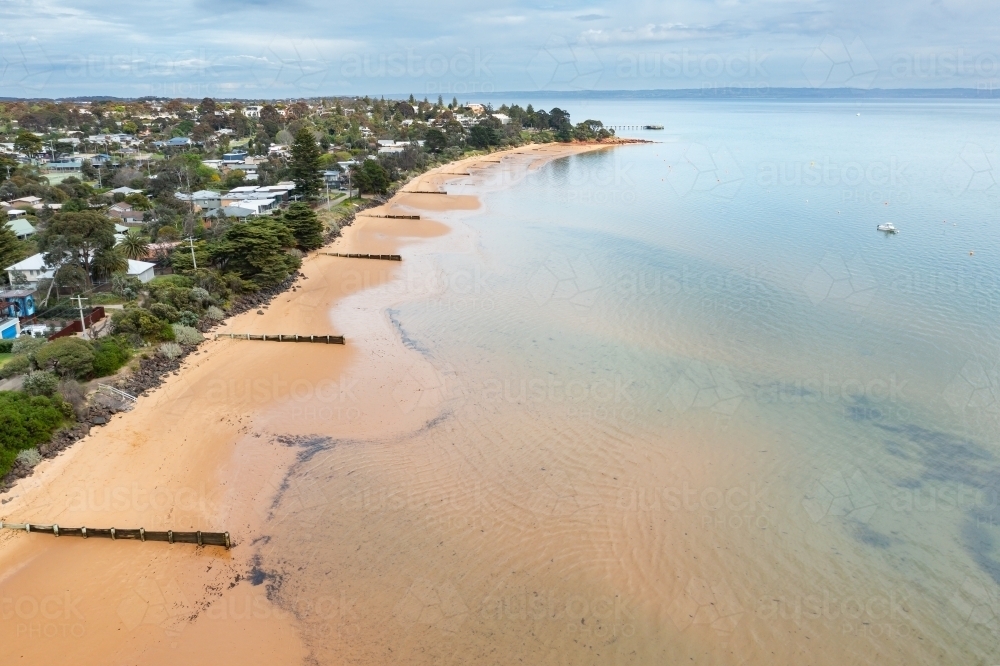 Image of Aerial view of a calm bay and golden sandy beach with lines of ...