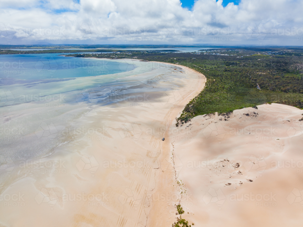 Image of Aerial view of a calm coastal bay and wide sandy beach below a ...