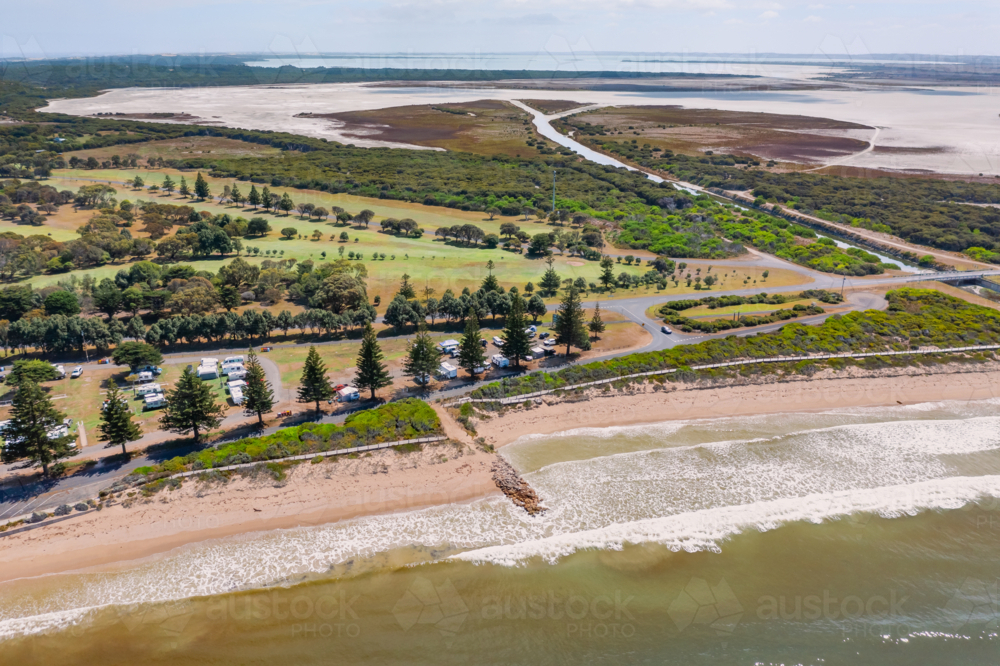 Image of Aerial view of a caravan park behind a coastal beach with salt ...
