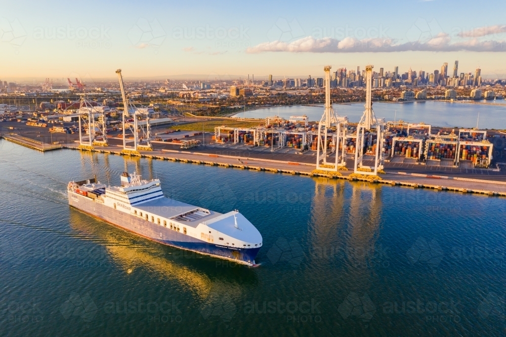 Image of Aerial view of a cargo ship leaving a city port - Austockphoto