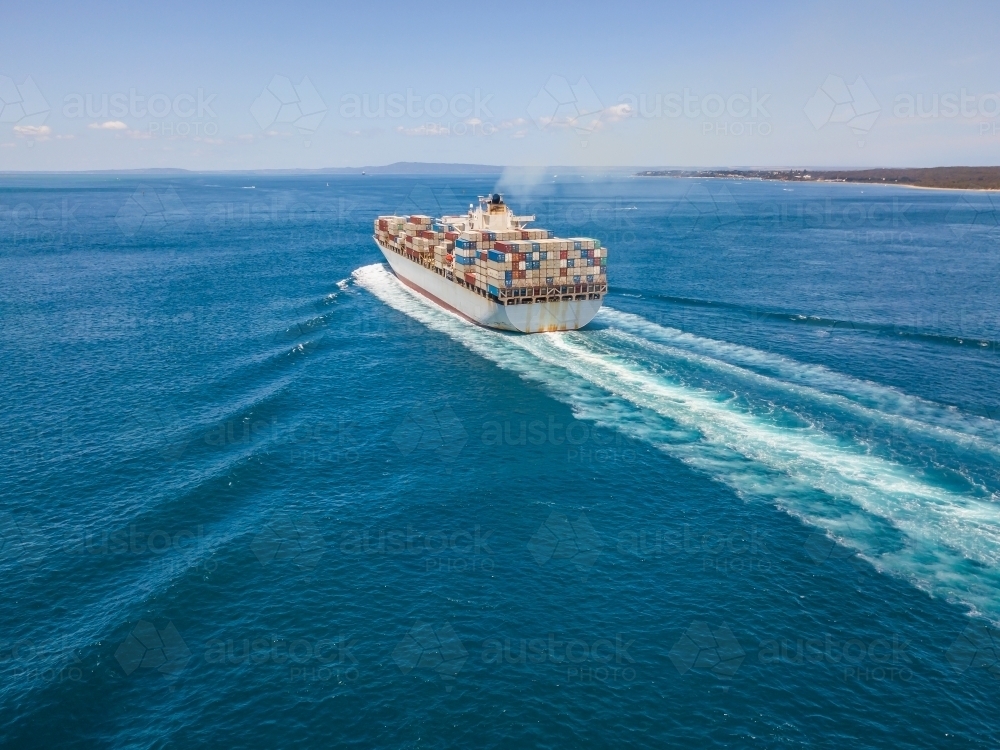 Image of Aerial view of a cargo ship steaming through calm blue water ...