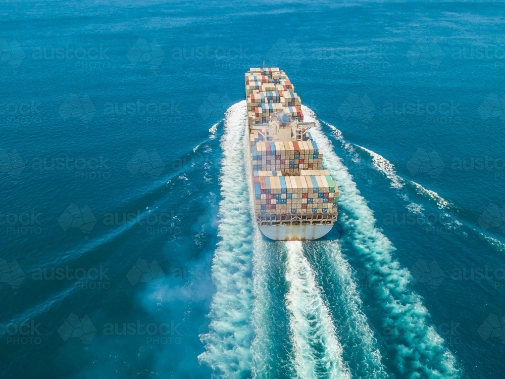 Image of Aerial view of a cargo ship steaming through calm blue water ...