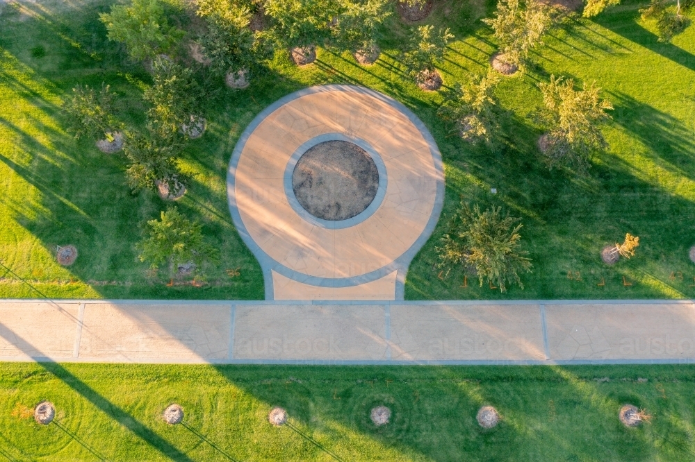 Image of Aerial view of a circular path in a lush green park with shadows cutting diagonally ...
