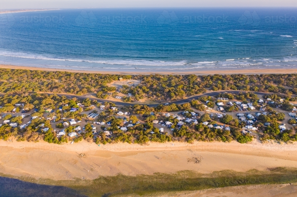Image of Aerial view of a coastal caravan park along a narrow sandy ...