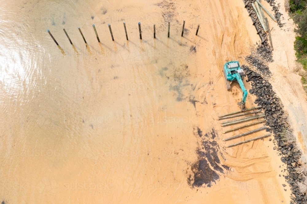 Image of Aerial view of a colourful digger working on a sandy beach ...