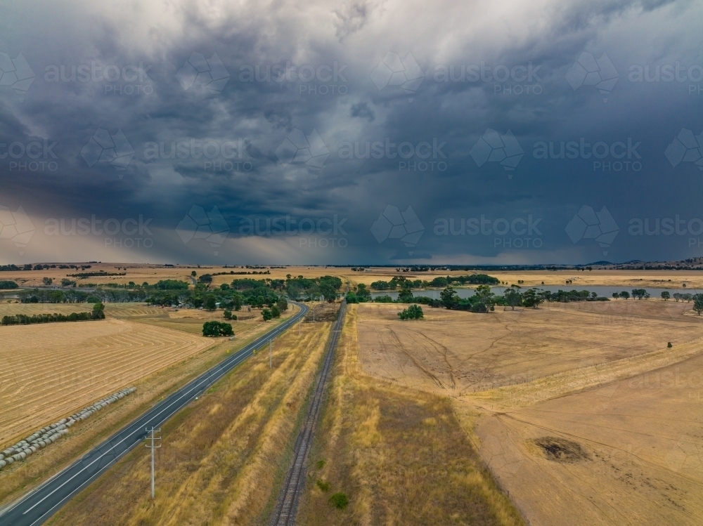 Image of Aerial view of a country road and railway lines across dry ...