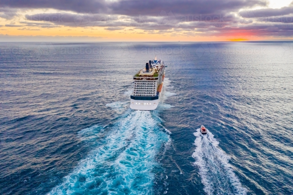 Image of Aerial view of a cruise ship heading out to sea at sunset ...