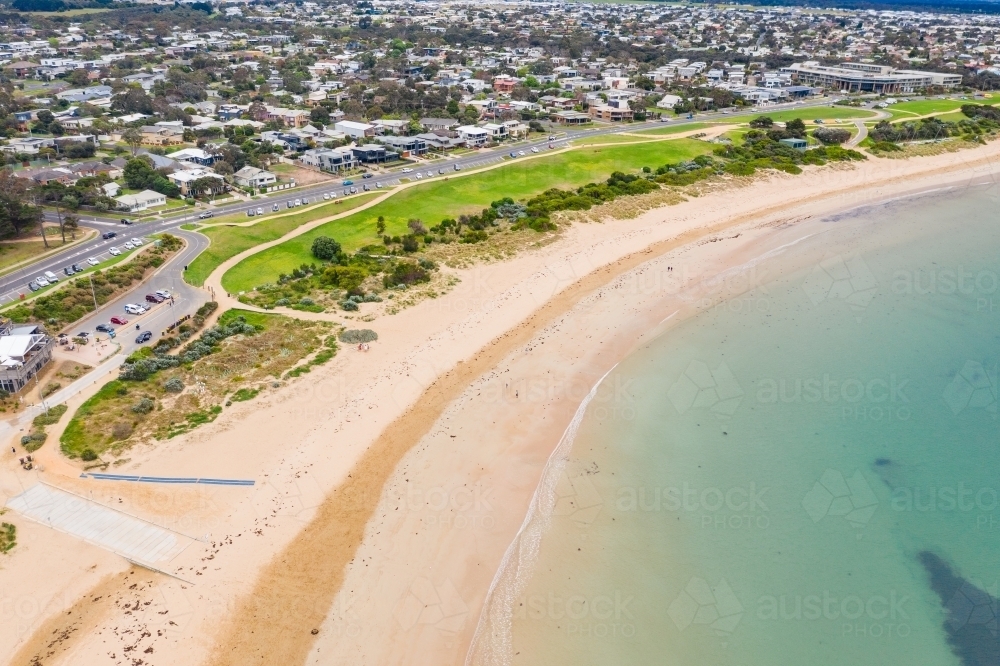 Image of Aerial view of a curved sandy beach in front of a grassy ...