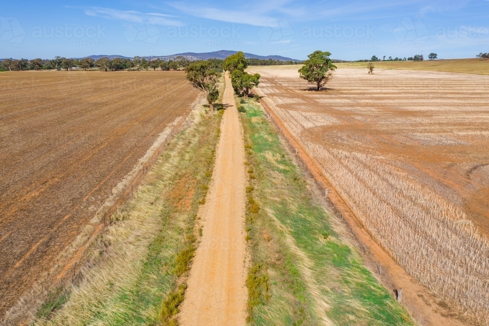 Image of Aerial view of a dirt road between paddocks of drying stubble ...