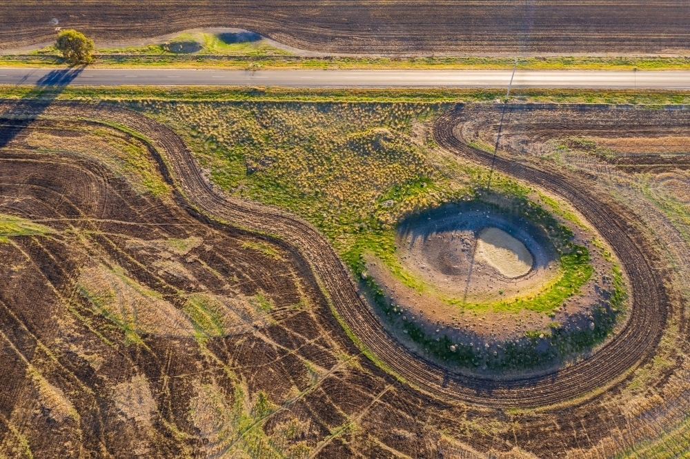Image of Aerial view of a dried dam on farmland surrounded by ploughed ...