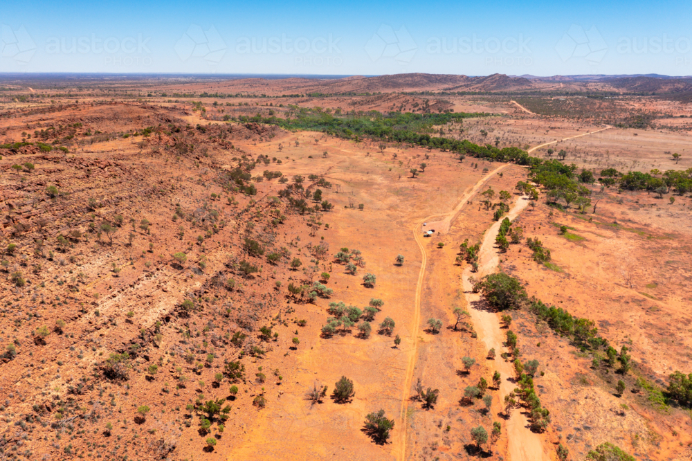 Image of Aerial view of a dry creek bed and remote dirt road running ...