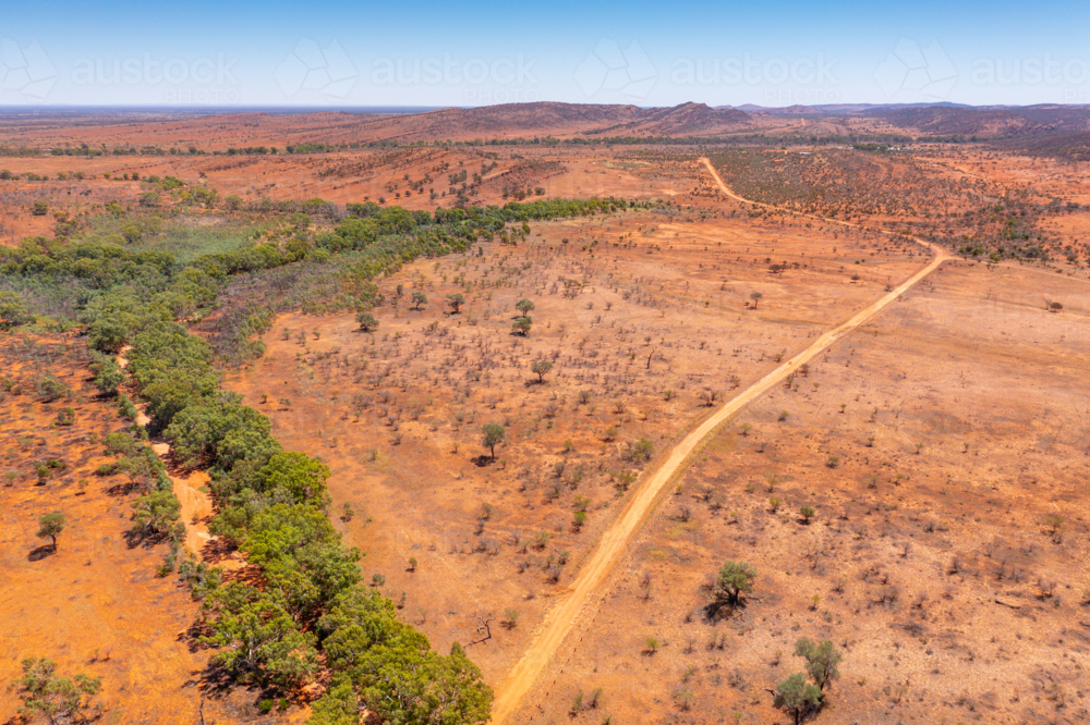 Image of Aerial view of a dry creek bed and remote dirt road running ...