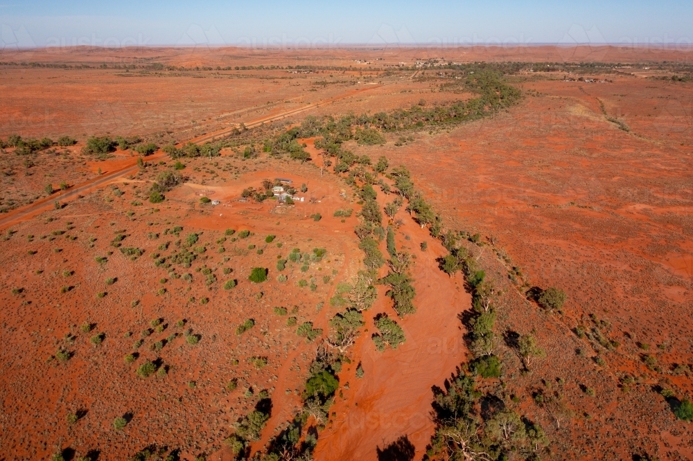 Image of Aerial view of a dry red soil river bed lined with gum trees ...