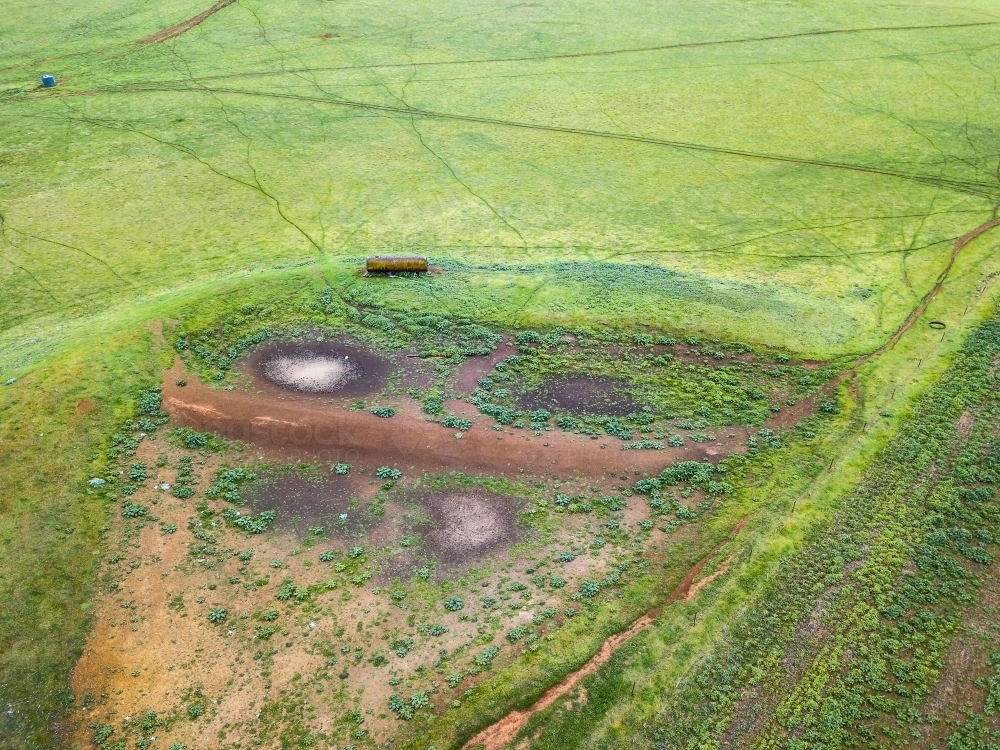 Image of Aerial view of a drying dam in a paddock of green grass ...