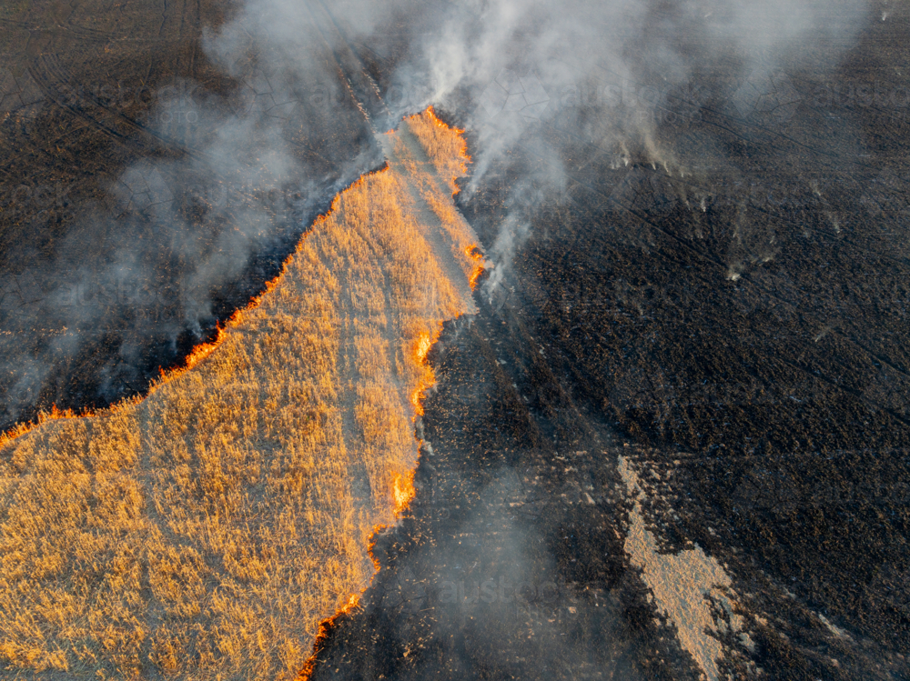 Image of Aerial view of a fire burning off stubble in a blackened ...