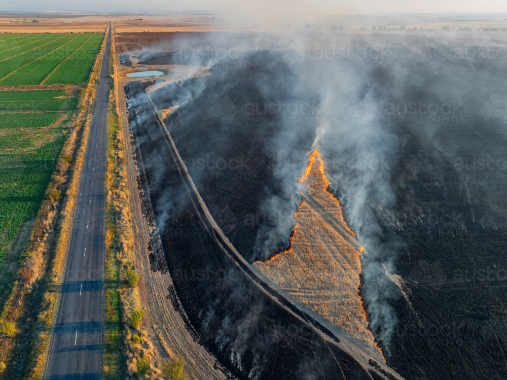 Image of Aerial view of a fire burning off stubble in a blackened ...