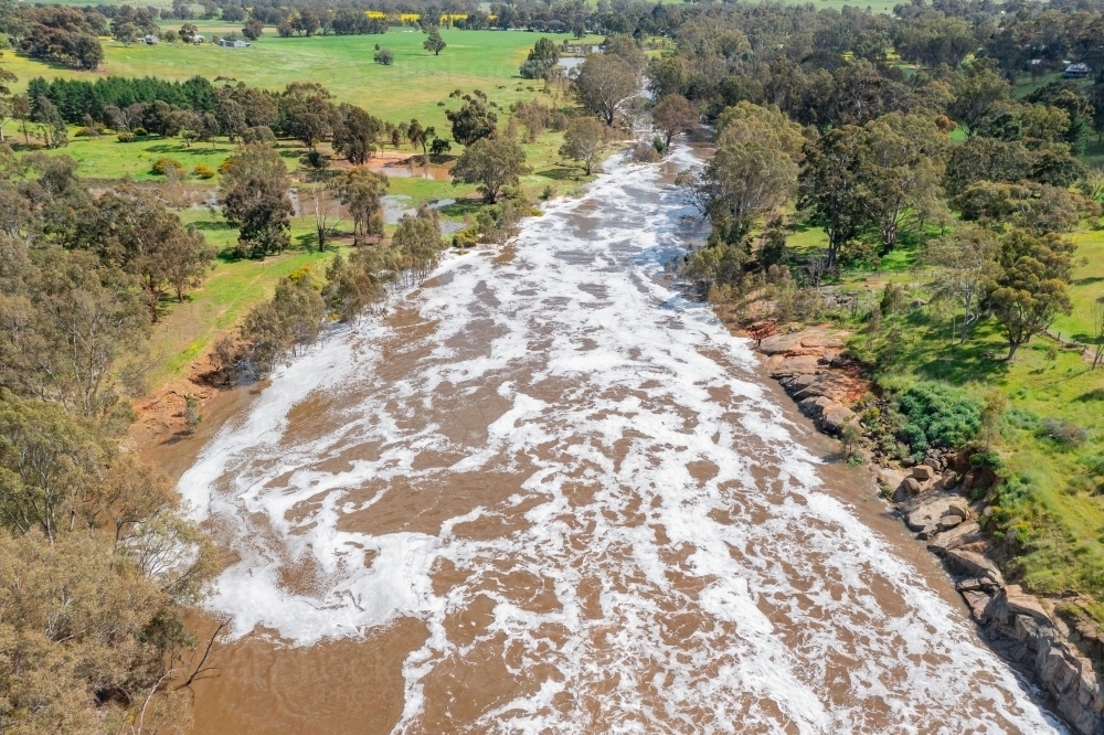 Image of Aerial view of a flooded river gushing with white water ...