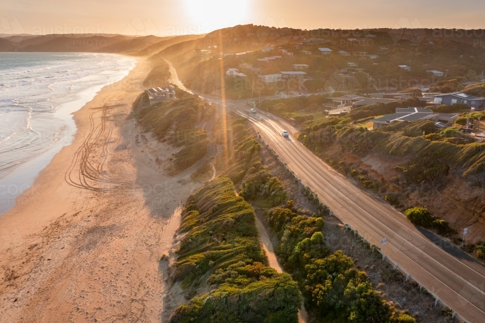 Image of Aerial view of a high coastal road above a sandy beach under a ...