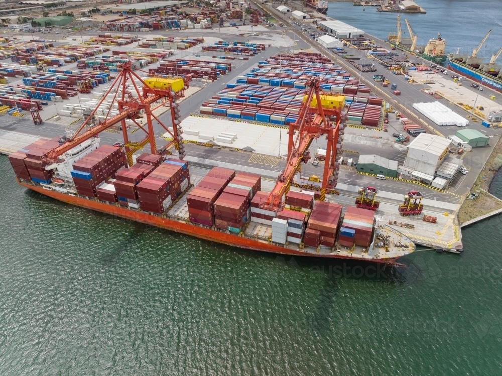 Image of Aerial view of a large cargo ship getting loaded with ...