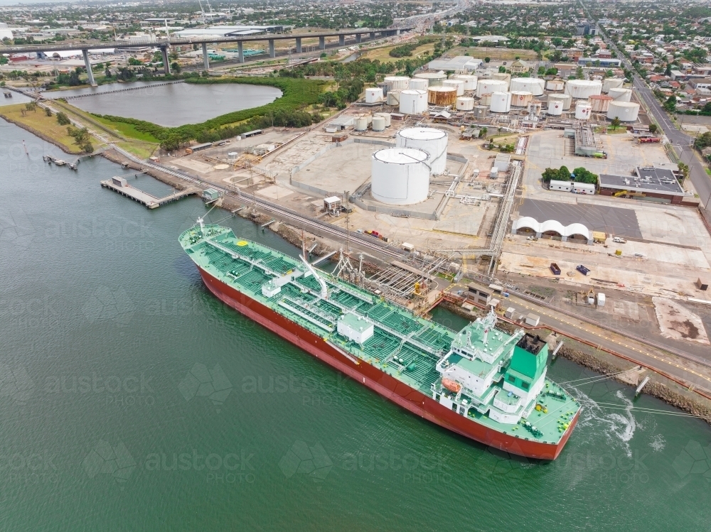 Image of Aerial view of a large tanker at port near storage tanks ...