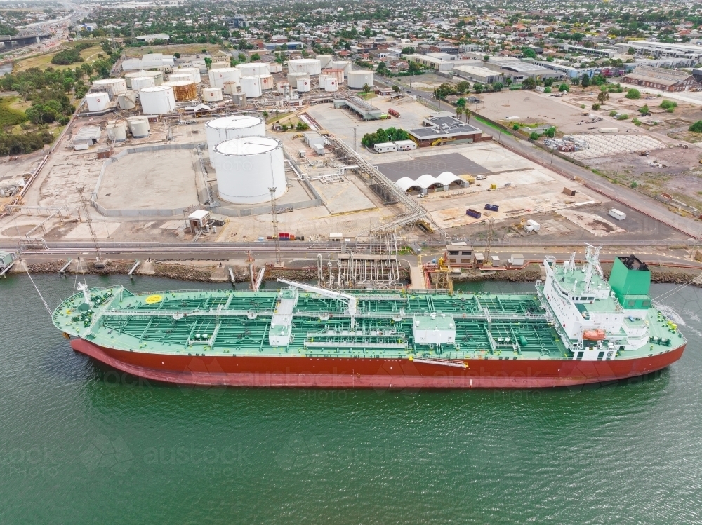 Image of Aerial view of a large tanker at port near storage tanks ...