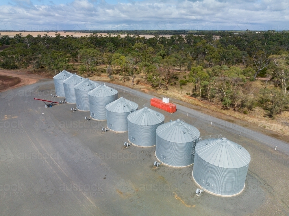 Image of Aerial view of a line of grain storage bins in a clearing on ...